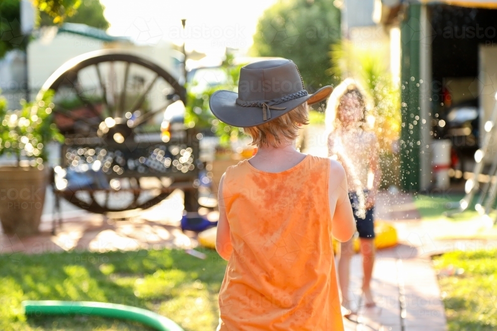 Image of Kids having backyard summer water fight - Austockphoto