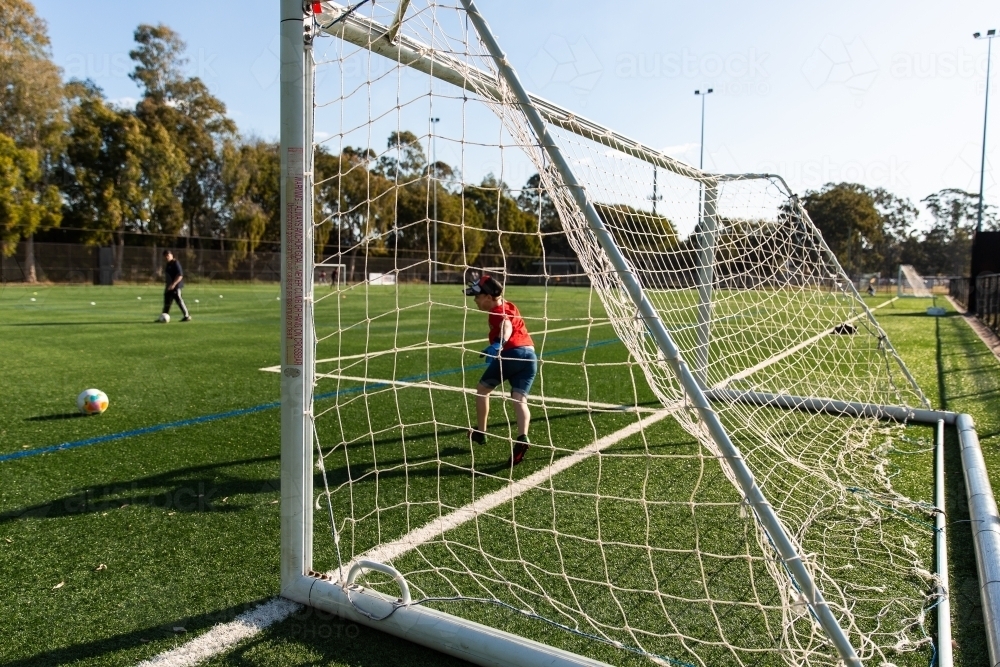 Image of kids learning to play soccer in goal - Austockphoto