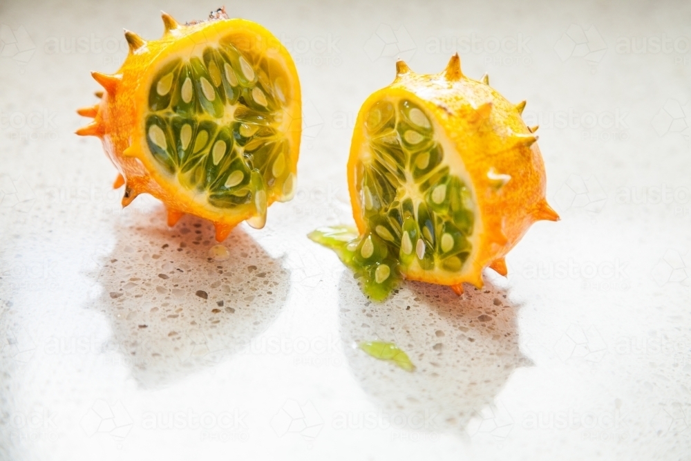 Image of Kiwano cut in half sitting on a stone bench - Austockphoto