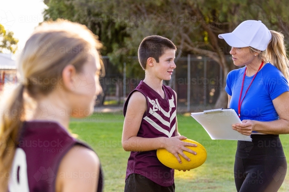 Image of lady coaching kids at aussie rules football - Austockphoto