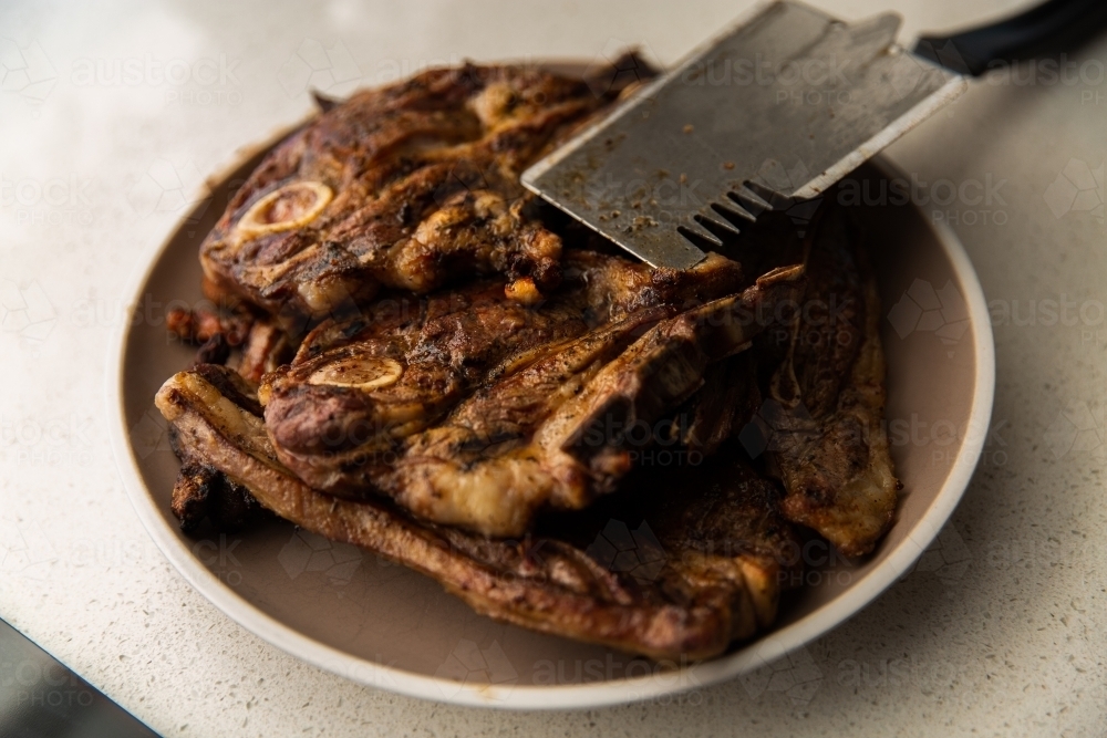 Image of lamb chops on a plate with a barbecue tool - Austockphoto