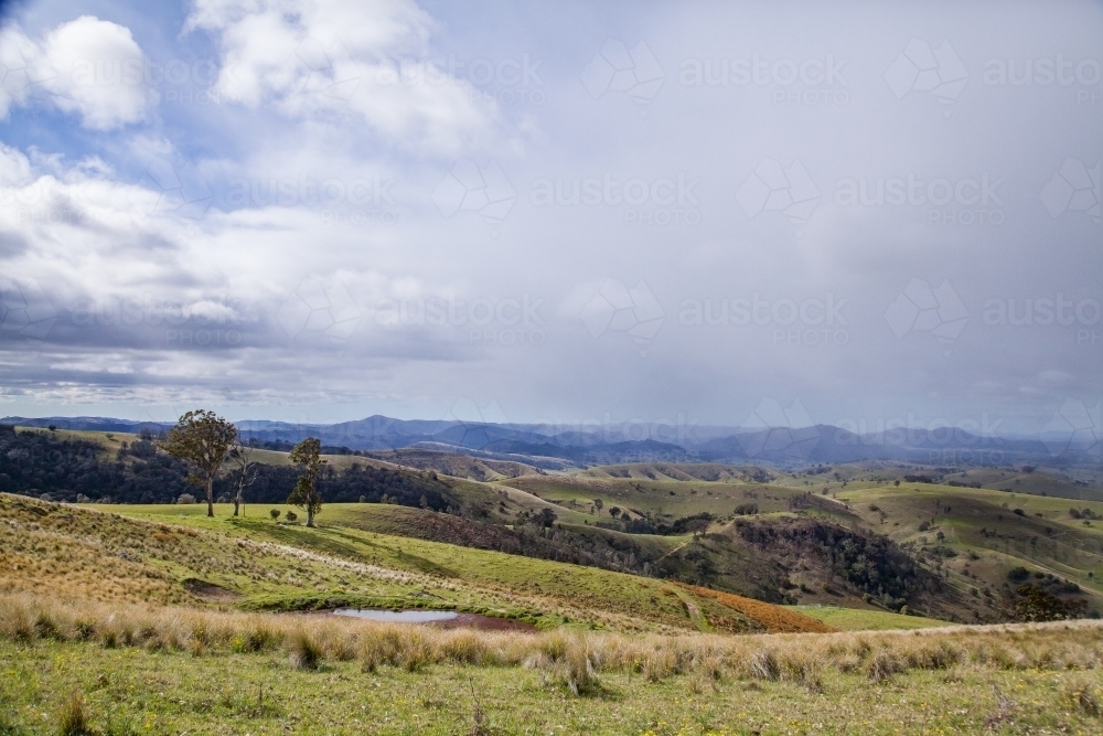 Image of Landscape of rolling hills and distant rain - Austockphoto