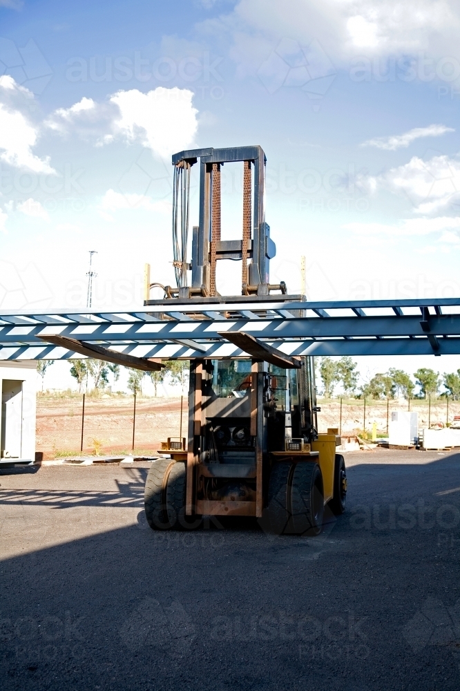 Image of Large forklift carrying metal framework on a work site ...