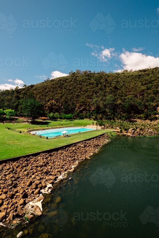 Image of large outdoor public pool by a lake - Austockphoto