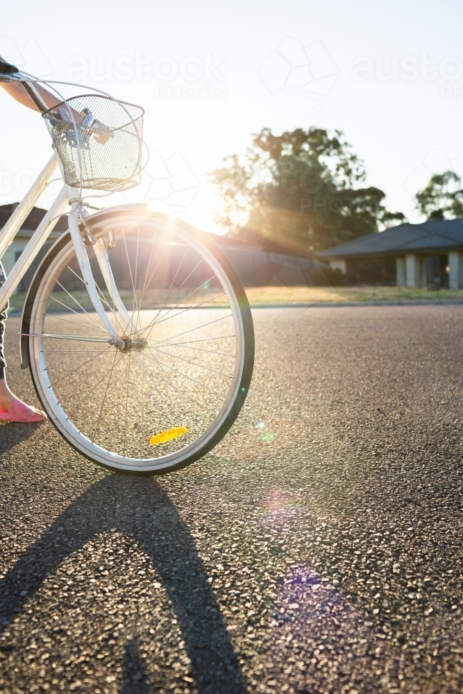 Image of Late light flare though wheel of kids bike on street casting ...