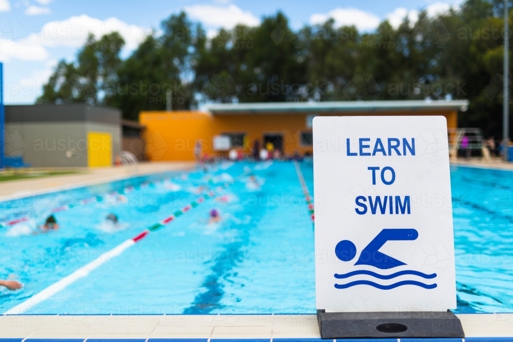 Image of Learn to swim sign at a swimming pool - Austockphoto