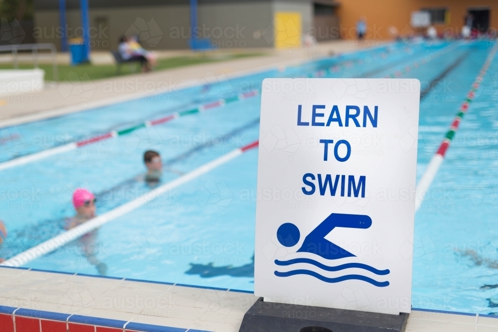 Image of Learn to swim sign at a swimming pool - Austockphoto