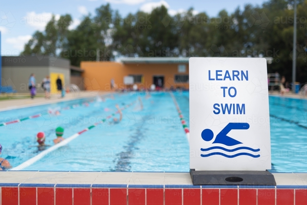 Image of Learn to swim sign at a swimming pool - Austockphoto