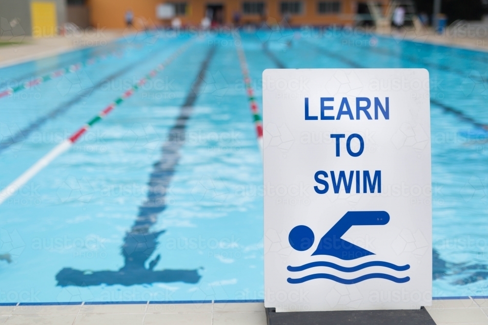 Image of Learn to swim sign at a swimming pool - Austockphoto