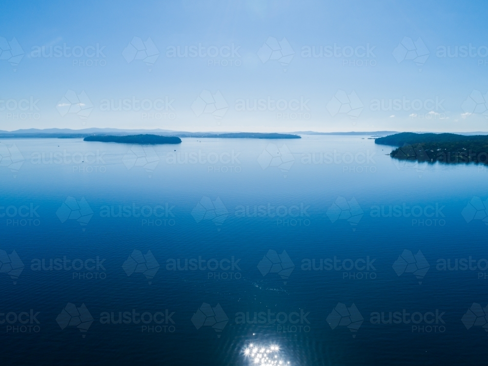 Image of Light sparkling on blue water of calm coastal lake seen from ...