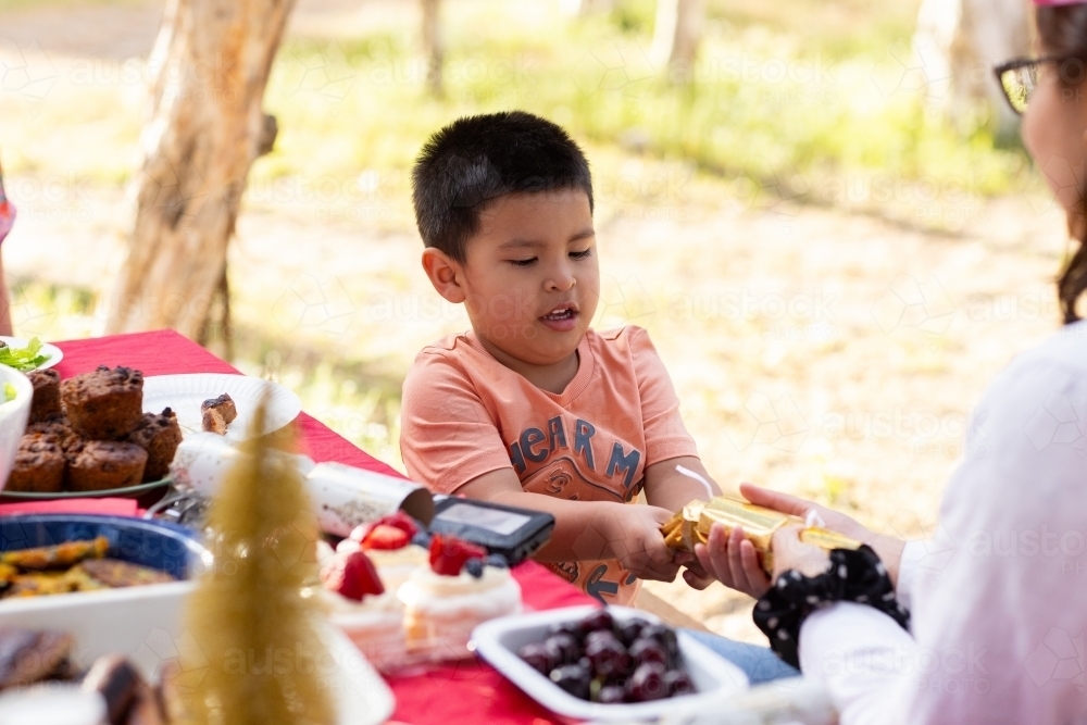 Image of little black-haired boy pulling a Christmas cracker with ...