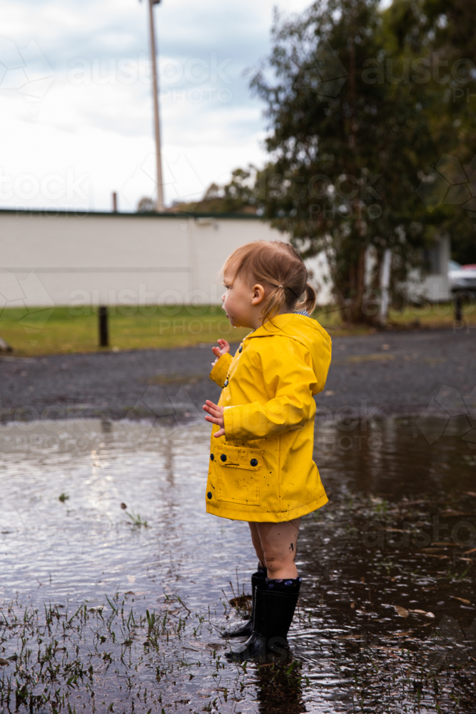 Image of little blonde haired girl in a puddle - Austockphoto