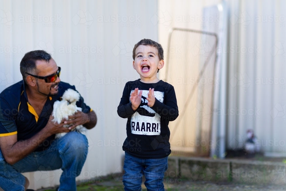 Image of Little boy excitedly clapping hands and father with chicken ...