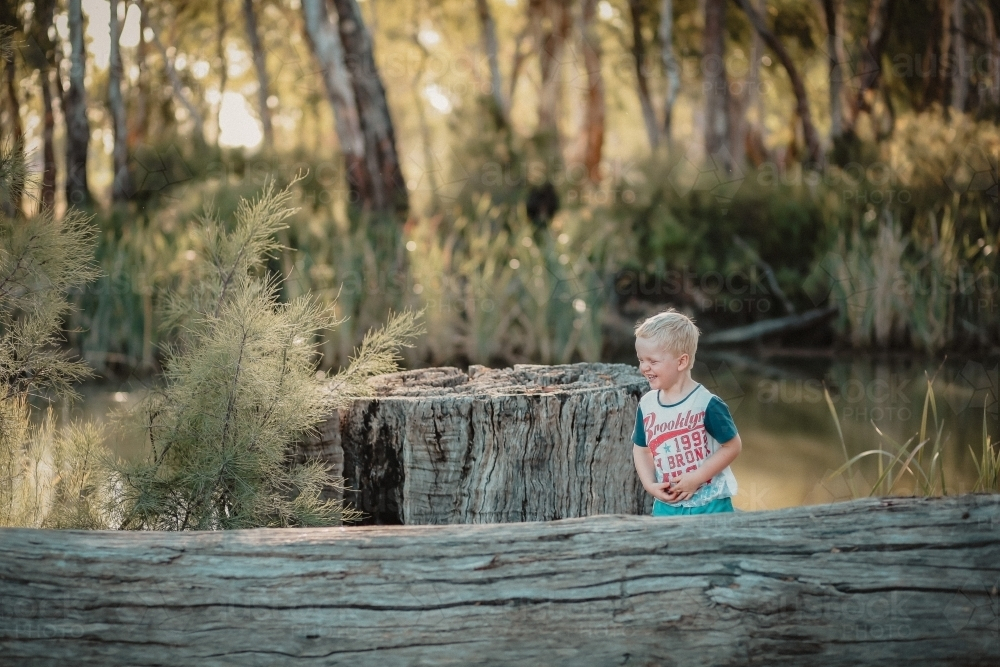 Image of Little boy laughing on an outdoor adventure beside a river ...