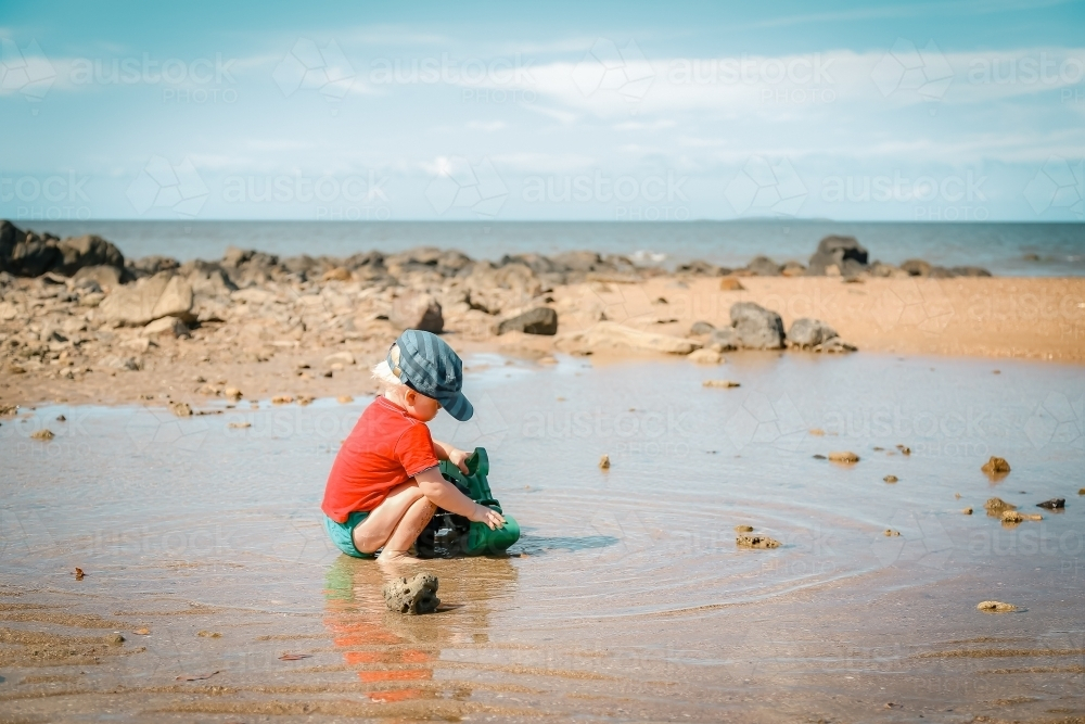 Image of Little boy playing with green digger toy on the beach ...