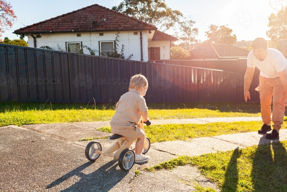 Image of Little boy riding trike on driveway of home on sunny day ...