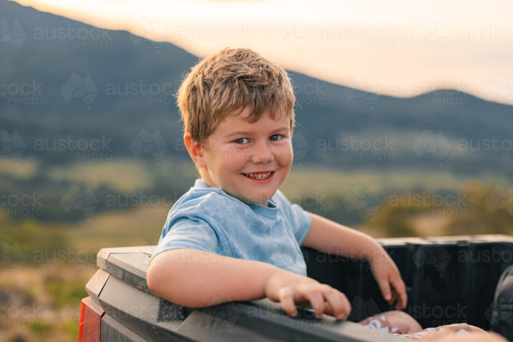 Image of Little boy sitting in back of off-road buggy on farm ...