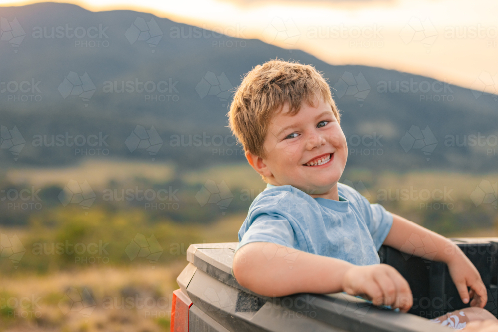 Image of Little boy sitting in back of off-road buggy on farm ...