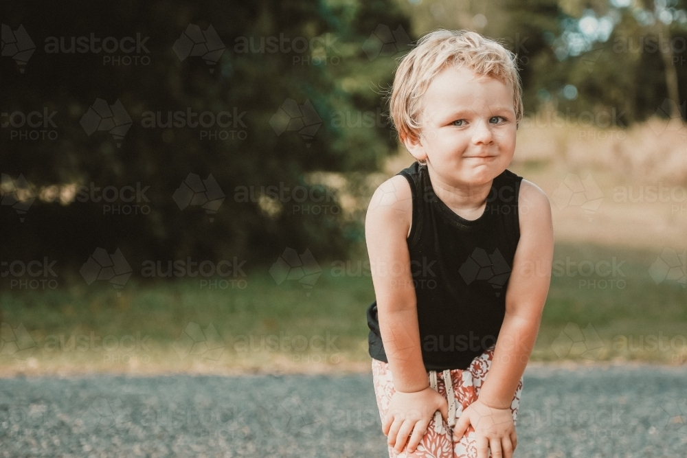 Image of Little boy standing outdoors with cheeky expression - Austockphoto