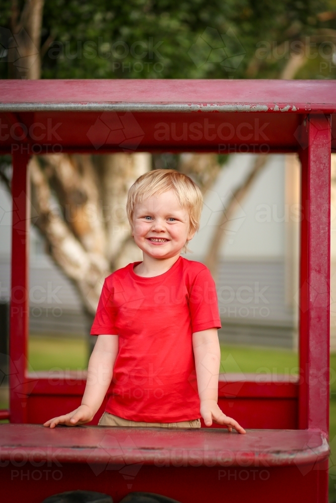 Image of Little boy wearing red shirt playing at playground - Austockphoto