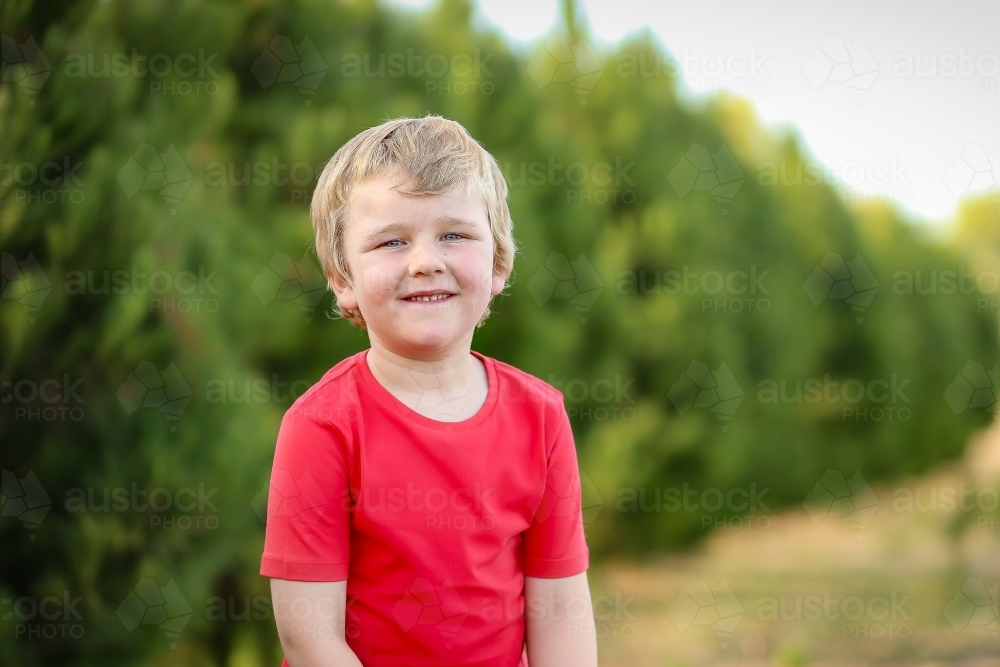 Image of Little boy wearing red shirt smiling in front of row of ...