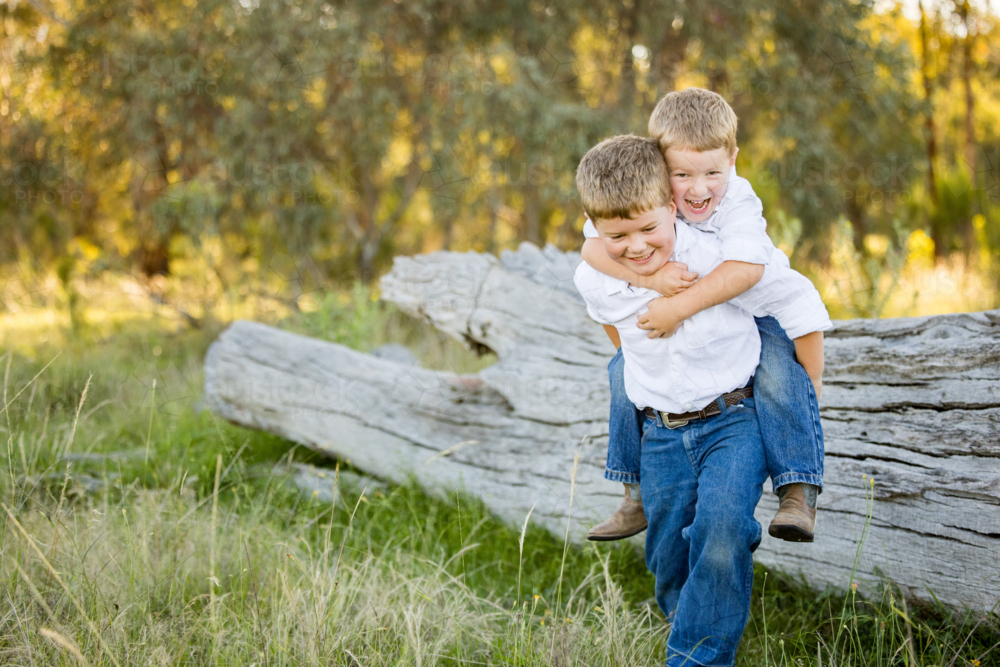Image of Little boys doing piggy back ride in rural Australian bush ...