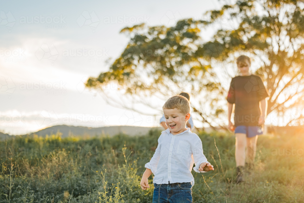 Image of Little boys exploring hilltop with teenager in golden ...