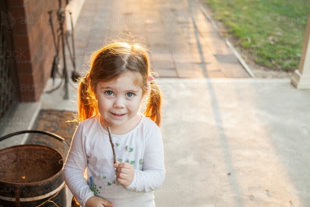 Image of Little girl collecting tiny sticks for kindling for wood fire ...