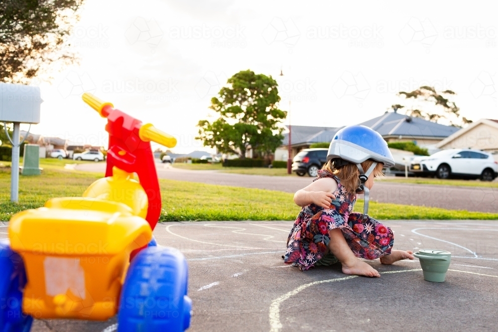 Image of Little girl drawing with chalk and eating snacks on suburban ...