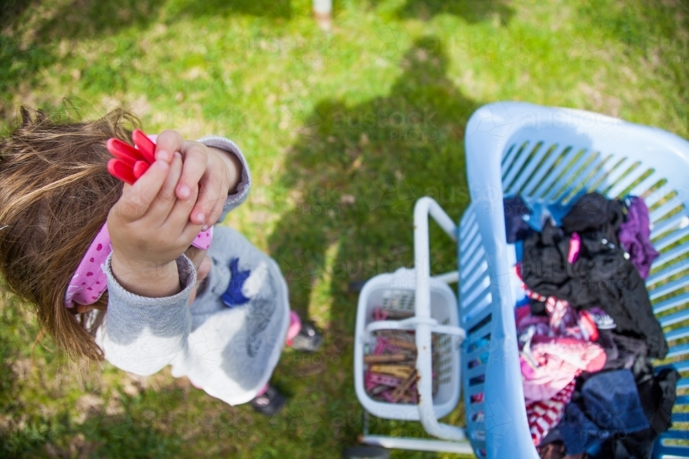 Image of Little girl helping with washing by handing pegs up - Austockphoto