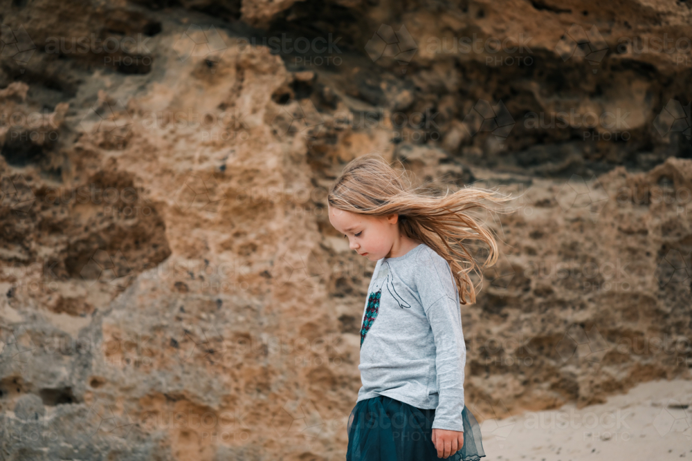 Image of Little girl in blue tutu walking on rocks at the beach ...
