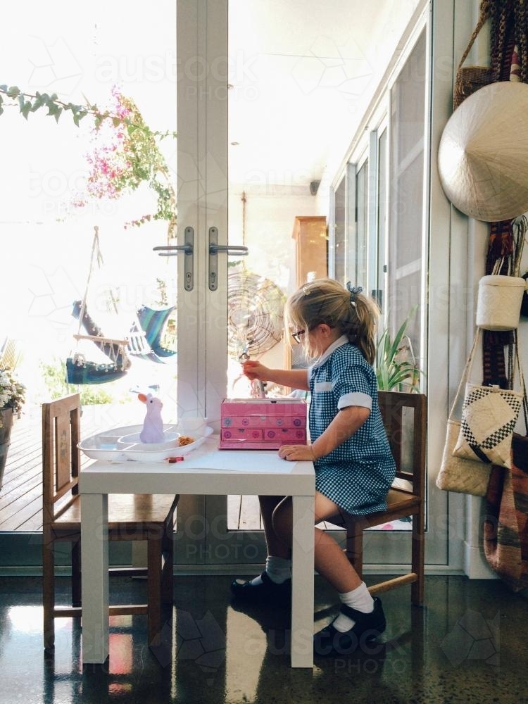 Image of Little girl in school uniform doing homework after school ...