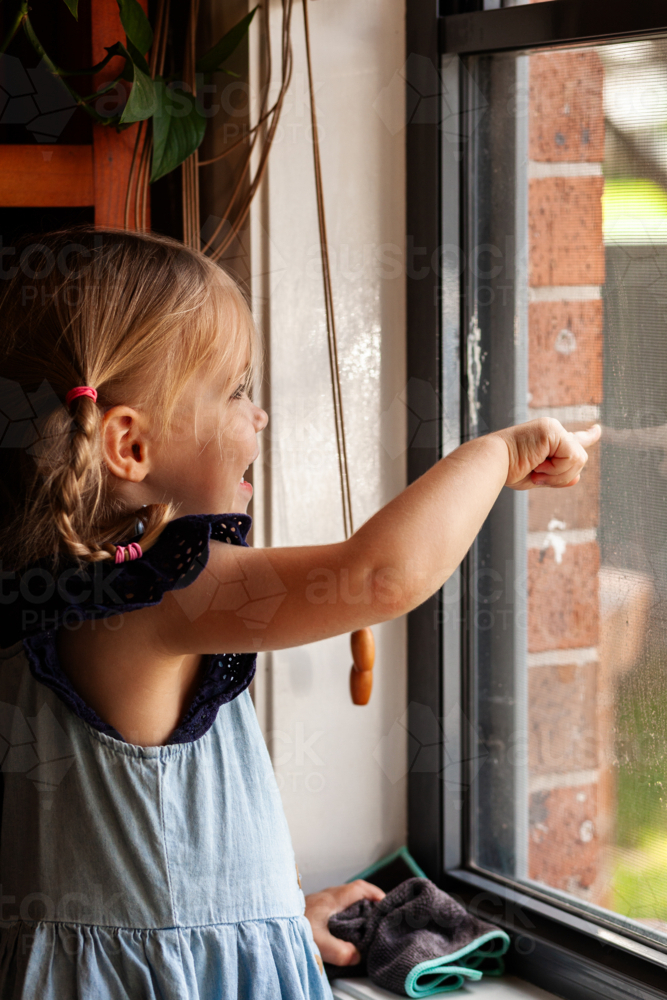 Image of Little girl indoors looking out front window of home ...