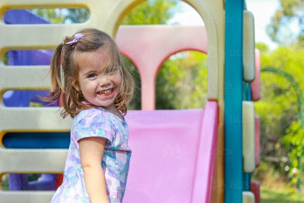 Image of Little girl looking over her shoulder and grinning - Austockphoto
