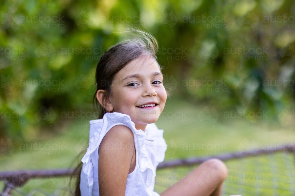 Image of little girl looking over shoulder smiling - Austockphoto