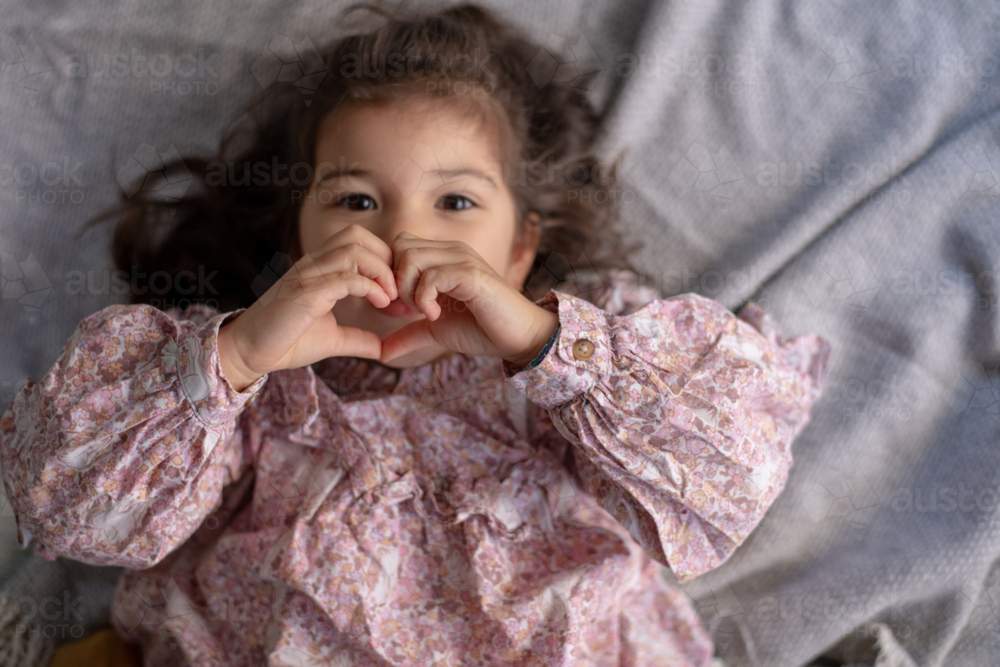 Image of little girl making heart hands - Austockphoto