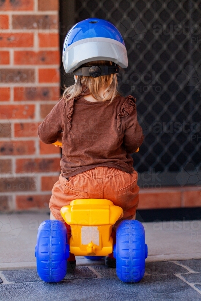 Image of Little girl riding away on tricycle - Austockphoto
