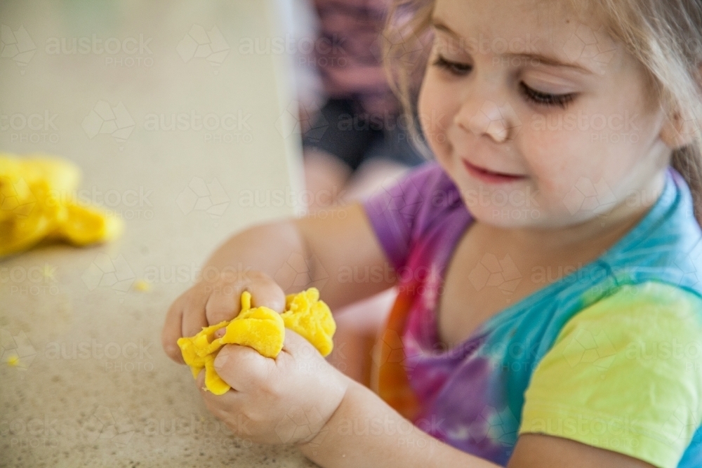 Image of Little girl squishing playdough in her fingers - Austockphoto