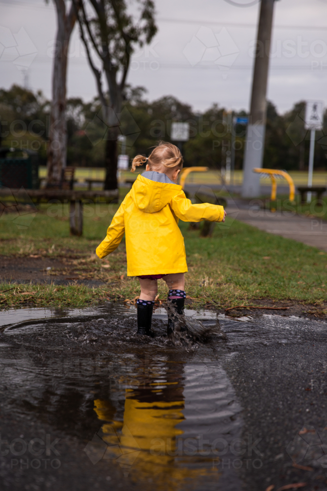 Image of little girl stomping in a puddle wearing bright yellow ...