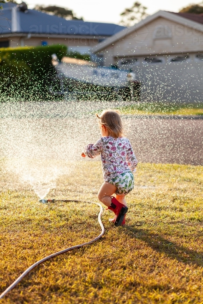 Image of Little kid wearing cloth nappy and red gumboots playing under ...