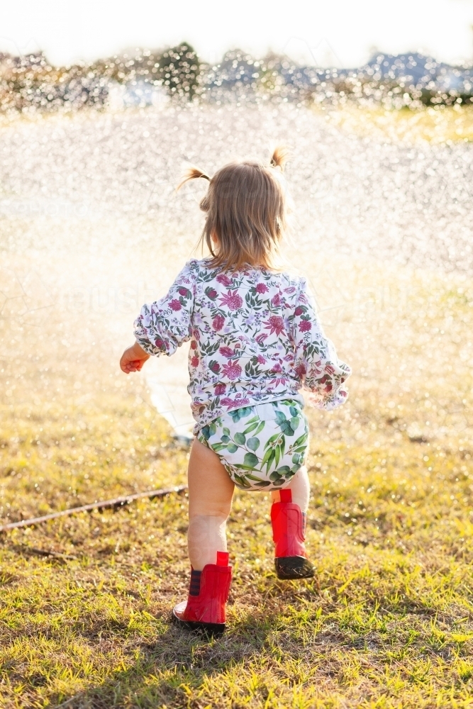 Image of Little kid wearing cloth nappy and red gumboots playing under ...
