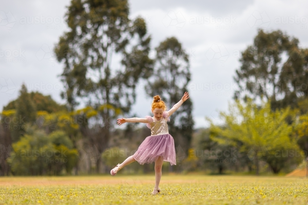 Image of little red-haired girl dancing in a park - Austockphoto