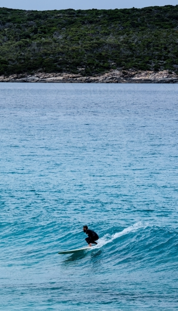 Image of Lone surfer riding wave on longboard with natural coastal ...