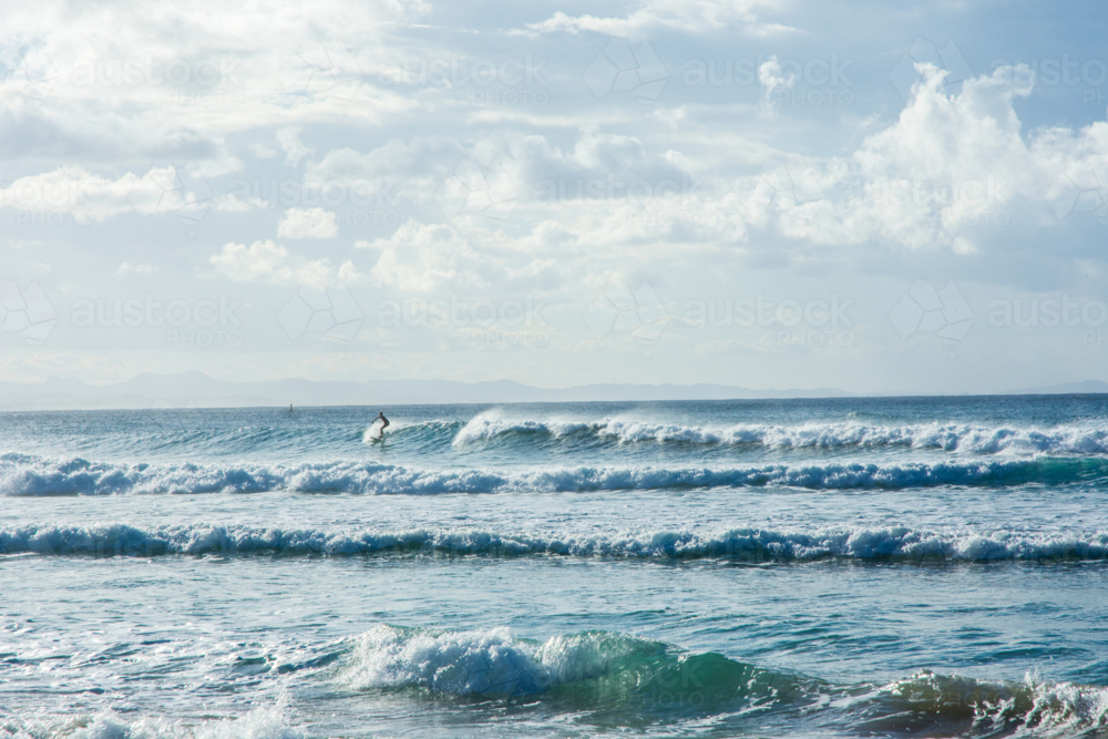Image of Lone surfer surfing a wave - Austockphoto