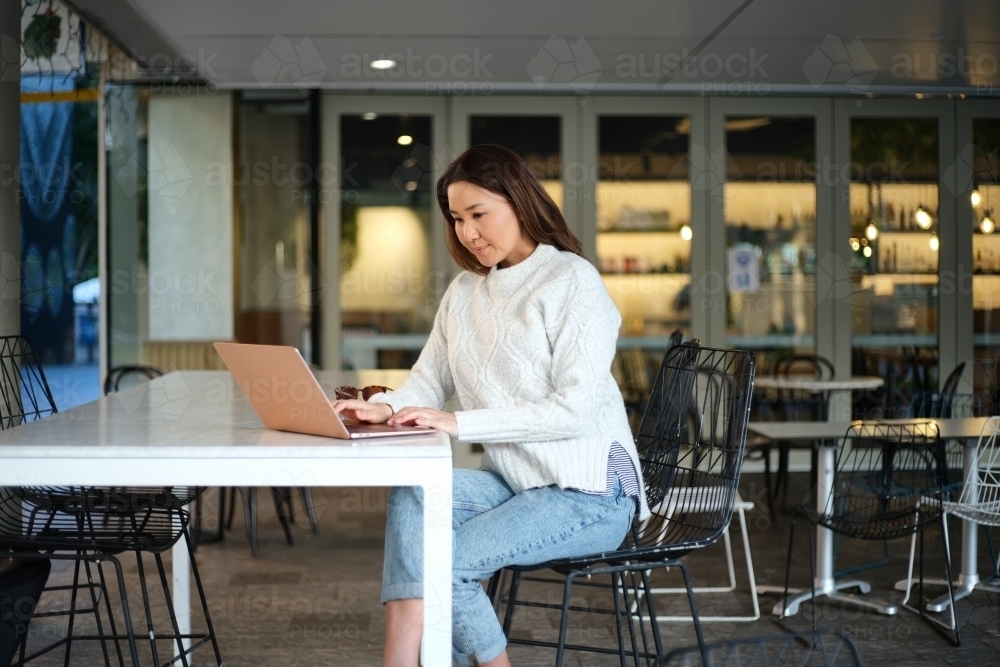 Image of Lone woman working on laptop in seated area - Austockphoto