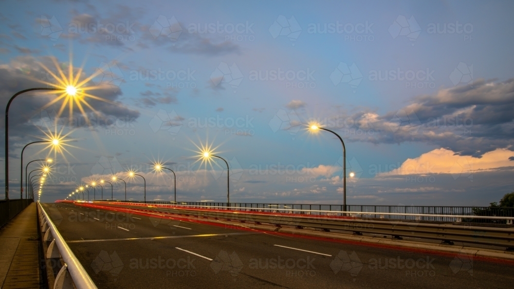 Image of Long exposure of cars driving over a bridge at dusk with the ...