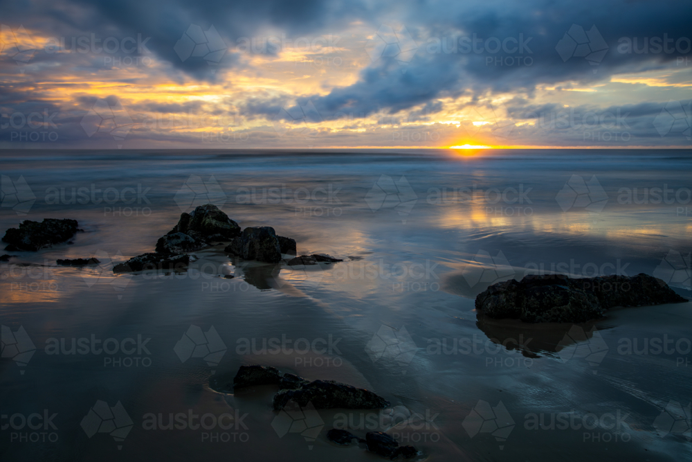 Image of Long exposure of ocean and boulders on beach at dawn ...