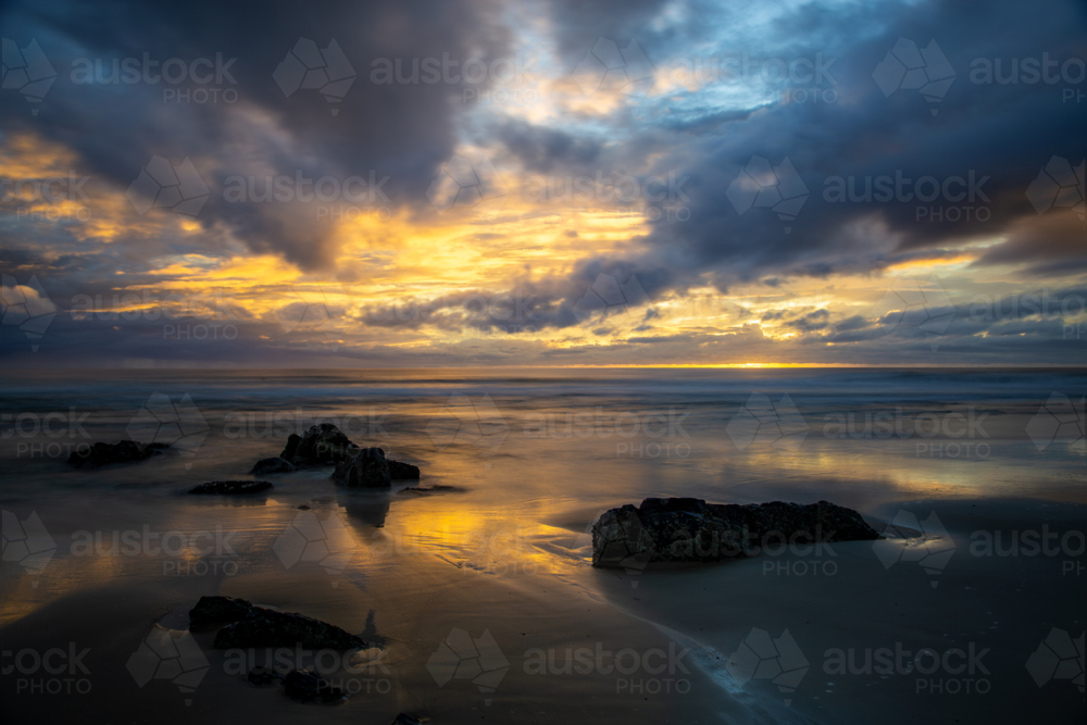Image of Long exposure of ocean and boulders on beach at dawn ...