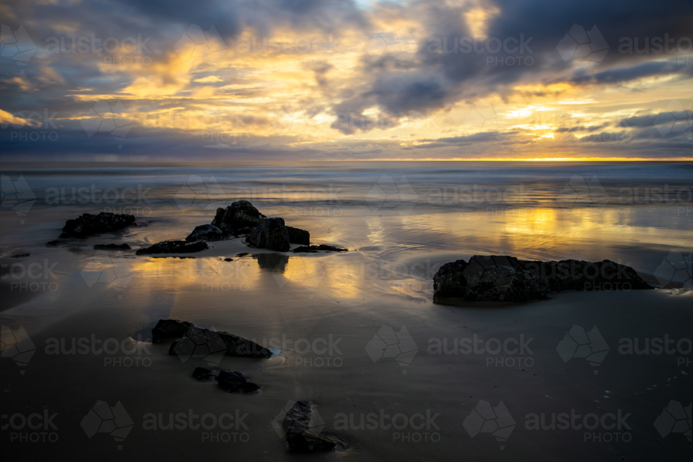 Image of Long exposure of ocean and boulders on beach at dawn ...