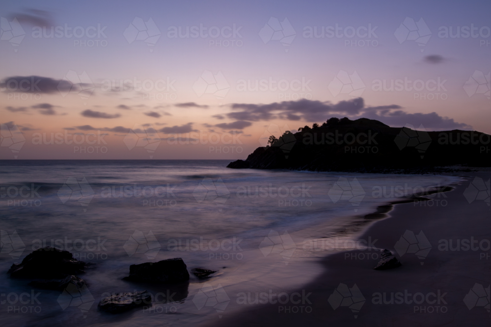 Image of Long exposure of the ocean and boulders on beach at dawn ...